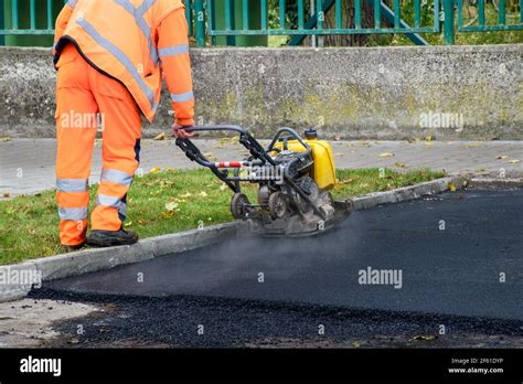 Paving Worker Uses Vibratory Plate Compactor To Compact New Asphalt