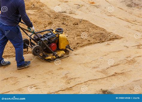 Worker Using Vibratory Plate Compactor For Compaction Sand During Path Construction Stock Photo
