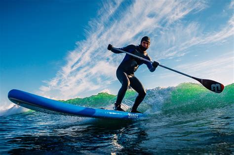 Stand Up Paddle Surfing On Waves Surfer In Wetsuit With Paddle Ride On