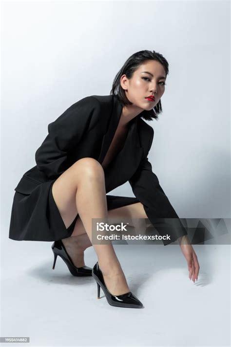 Asian Woman In Black Suit And Black High Heels Posing On White
