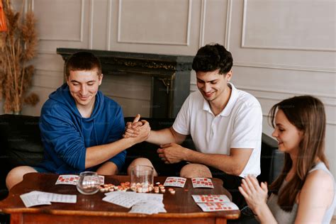 A Group Of People Sitting Around A Table Playing Cards Photo Board