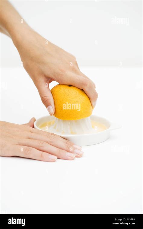 Woman squeezing orange with citrus press, cropped view of hands Stock Photo - Alamy