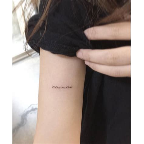 Handwritten Word Cosmos Tattoo Located On The Bicep
