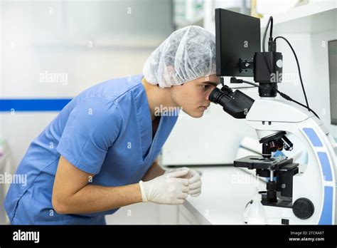 Young Veterinarian Examining Samples Under Microscope In Veterinary