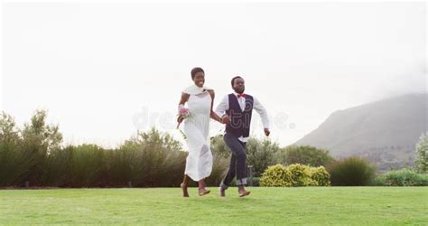 Happy African American Couple Holding Hands And Jumping During Wedding