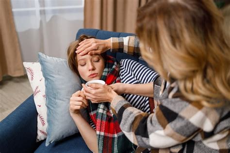 Madre Dando Té Caliente A Su Hija Con Fiebre Y Comprobando La Fiebre En