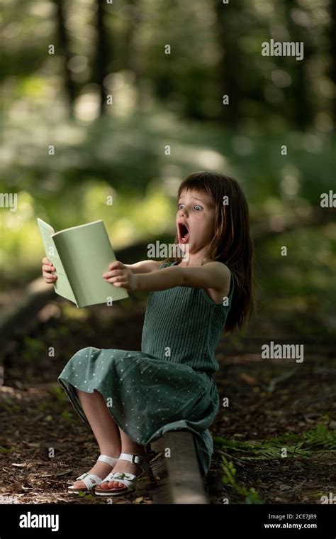 Amazed Preteen Girl In Summer Dress Sitting In Garden And Demonstrating