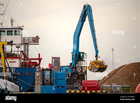 Cargo Ship And Cargo Handling Equipment A Ship Is Anchored In The Harbor And Various Cargoes Cargo Ship And Cargo Handling Equipment A Ship Is Anchored In The Harbor And Various Cargoes