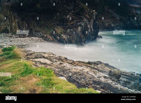 Bright Landscape Of Rocky Shore With Grass Washing By Foamy Turquoise