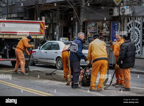 Workers In Orange Uniforms And Protection Equipment Fixing And Patching