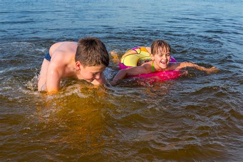 A Brother And A Sister Are Playing In The Water Outdoors Summer