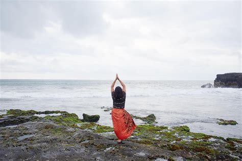 Asian Woman Wearing Native Sarong Of Bali Doing Yoga Poses On The Coast
