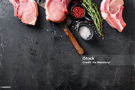 미국 의 고전적인 정육점 칼 또는 검은 슬레이트 테이블 상단에 향신료와 로즈마리와 고추와 칼 위에 설정 유기농 돼지 고기 갈비