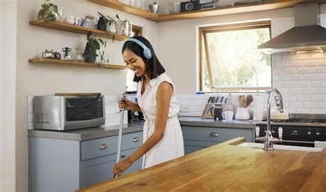 Premium Photo Happy Headphones And Woman Cleaning The Kitchen While