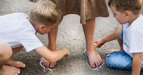 Two Small Sons Playing With Unrecognizable Mother On A Road In Park On