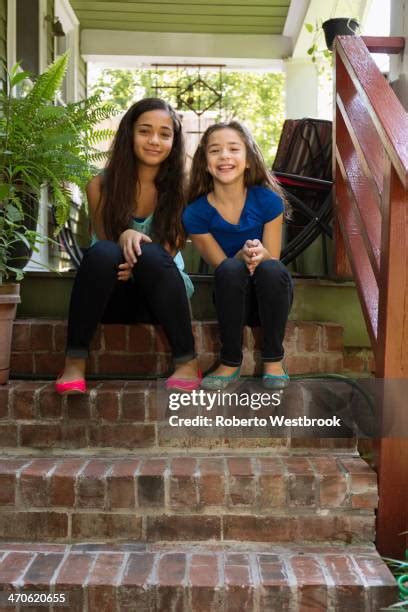 Mixed Race Sisters Sitting On Steps Photos And Premium High Res