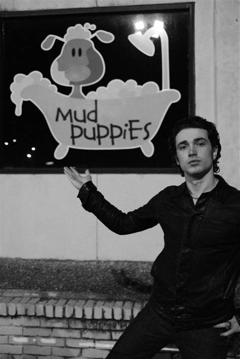A Man Standing In Front Of A Sign That Says Mud Puppies With A Cow On It