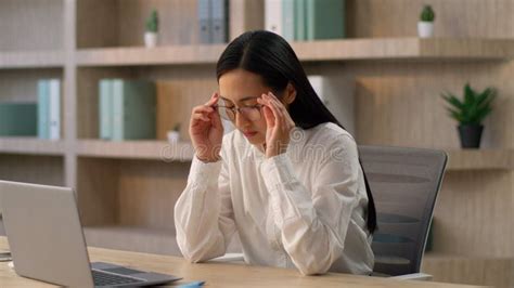 Stressed And Exhausted Asian Female Doctor At Her Office Desk Feeling