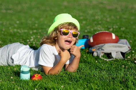 Niño divirtiéndose afuera niño jugando en el jardín niño feliz tirado en la hierba en la
