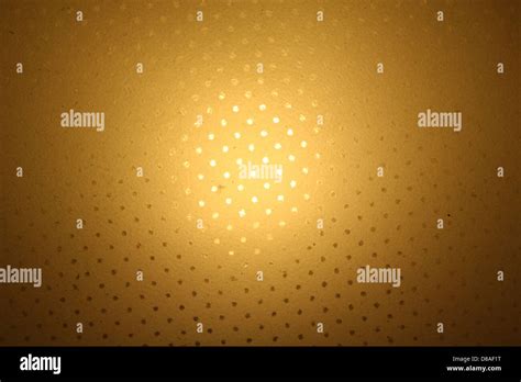 The Light Passing Through A Glass Shade With Small Holes Creates A