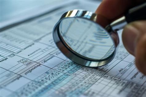 A Person Examining A Piece Of Paper Closely With A Magnifying Glass Conducting Regular Data