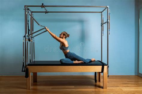 A Young Girl Does Pilates Exercises With A Bed Reformer Barrel Machine