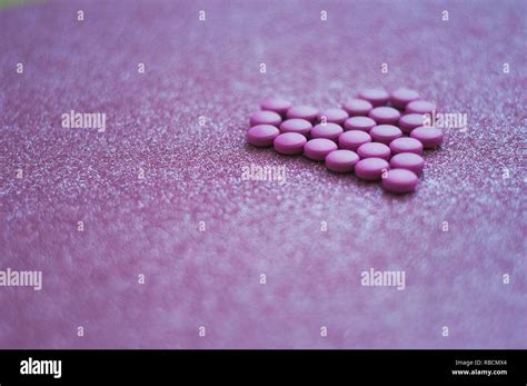 Pink Pills Laid Out In Shape Of A Heart On Glitter Pink Background