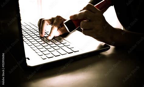Anonymous Hacker Typing On Keyboard Of Laptop For Remotely Hacking And Receiving Personal