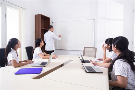 사무실에서 비즈니스 회의 컨퍼런스 세미나를 갖는 의료 인력의 그룹 화이트보드 옆에 서 있는 프레젠테이션을 들고 명랑한 의사 연사를 주의 깊게 듣는 팀원들 20 24세에 대한