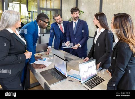 Group Of Multiracial Colleagues In Formal Wear Discussing Graphs And