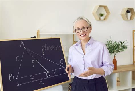 Portrait Of A Happy Math Teacher Standing By The Blackboard In The