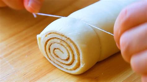 A Person Is Holding A Needle And Thread To A Rolled Up Pastry