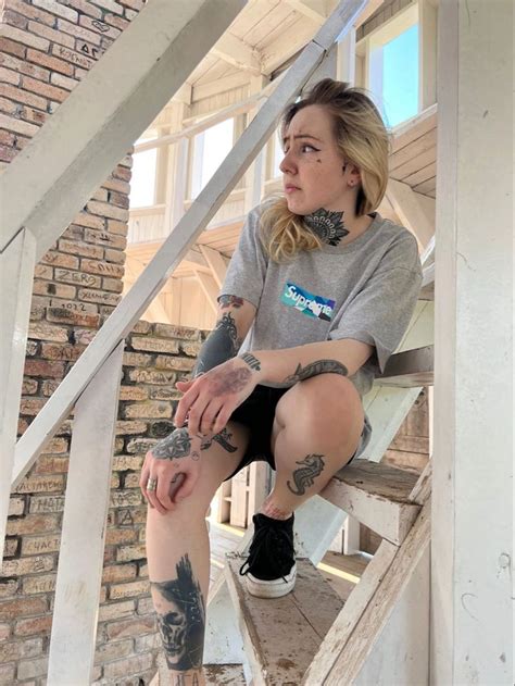 a woman sitting on top of a white stair case next to a brick wall and ...