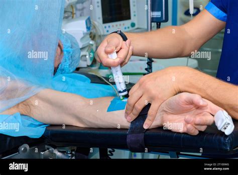 An Anesthesiologist Injects Intravenous Anesthesia With A Large Syringe Into The Patients Arm