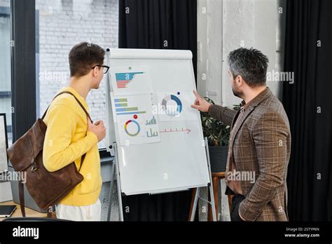 Two Colleagues Engage In An Onboarding Session Discussing Charts And Two Colleagues Engage In An Onboarding Session Discussing Charts And