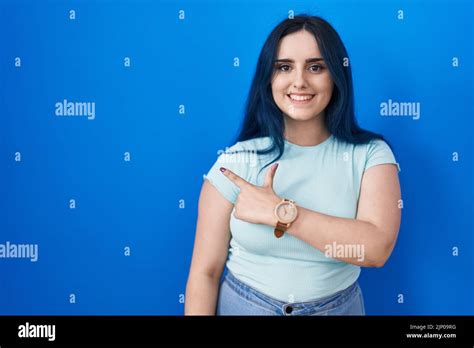 Young Modern Girl With Blue Hair Standing Over Blue Background Cheerful