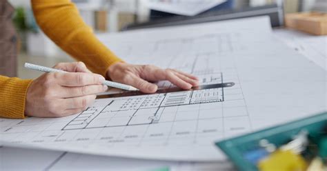 알아볼 수 없는 여성 건축가가 사무실 책상에서 일하는 동안 청사진을 그리는 클로즈업 복사 공간 사진 Unsplash의