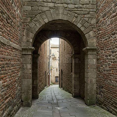 Narrow Cobblestone Alley With High Stone And Brick Walls Leading