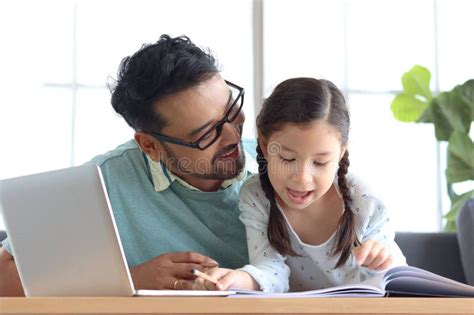 Father Teaches Cute Girl Daughter To Do School Homework Using Laptop Computer For E Learning