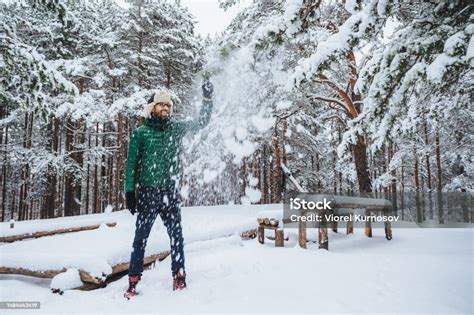 따뜻한 옷을 입은 잘생긴 수염 난 남성의 야외 촬영 공중에 눈을 던지며 재미있게 놀고 겨울 숲에서 휴가를 보내고 긍정을 표현합니다 레크리에이션과 날씨 개념 40 44세에