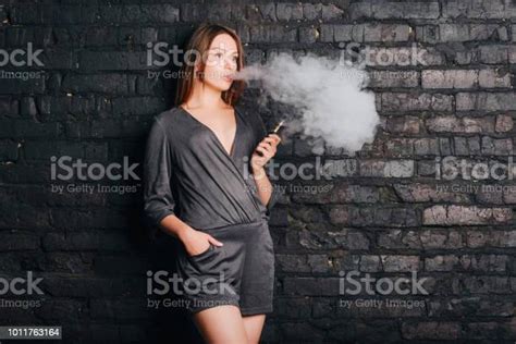 유행 아름 다운 소녀 담배 무료 담배 흡연 연기 벽돌 벽 바탕에 서의 큰 구름을 길게 세련 된 옷을 입은 관능에 대한 스톡 사진 및 기타 이미지 Istock