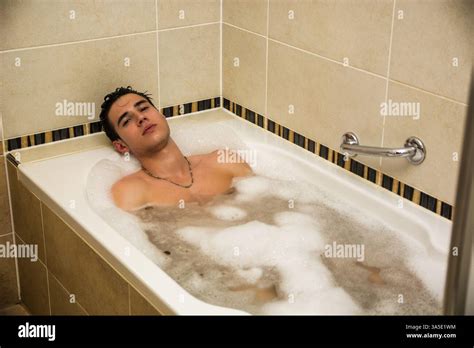Handsome Young Man In Bathtub At Home Having Bath Looking At Camera