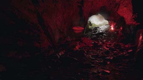 Premium Photo Man Moving Inside The Dark And Mysterious Cavern With A Red Burning Signal Flare