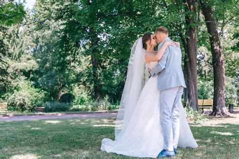 Premium Photo Happy Couple Bride And Groom Hug And Stand In A Green Park