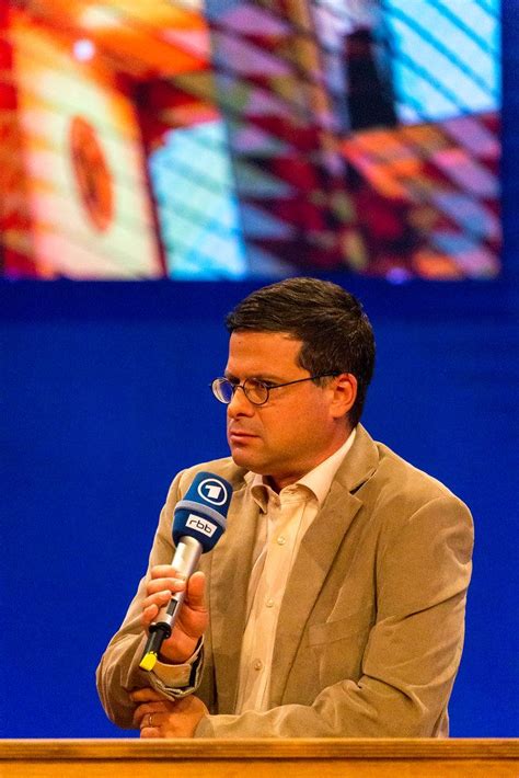 Political Scientist Prof Gideon Botsch Standing At The Wooden Desk In Front Of A Blue