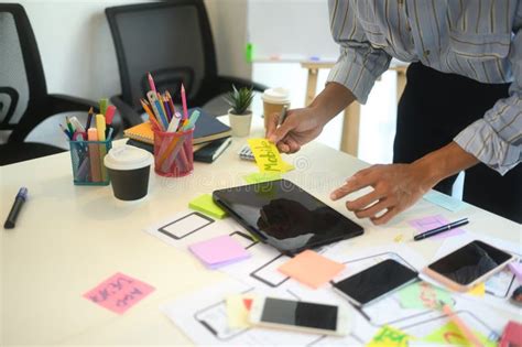 Team Of Creatives Collaborating On A Ux Ui Project At Workspace Filled With Flowcharts And