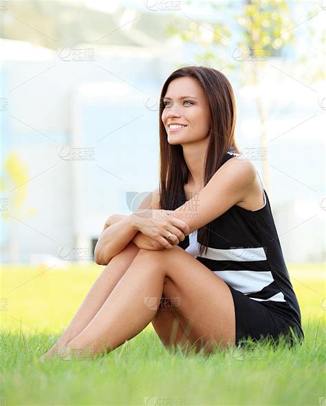 年轻貌美的商业女人坐在户外的草地上