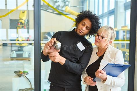 Engineers Inspecting Robotic Gripper Part In Industrial Workspace For Automation Process Stock