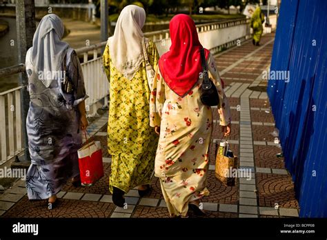 Three Women In Traditional Dress Walk Past With Shopping Bags In