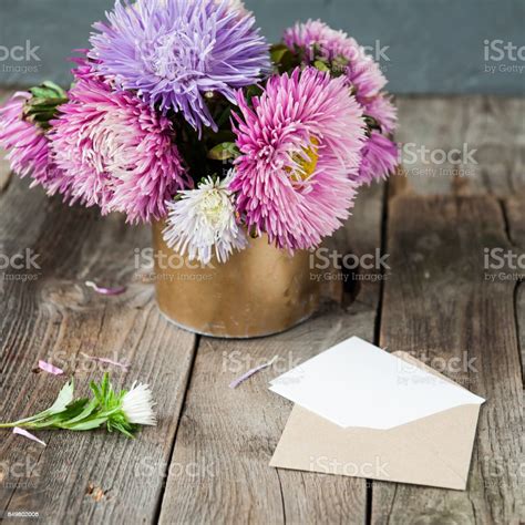 여러 가지 빛깔과 꽃 꽃 꽃다발 빈 흰색 인사말 카드와 소박한 나무 테이블에 어두운 회색 배경 공예 종이 봉투 엽서를 모의입니다